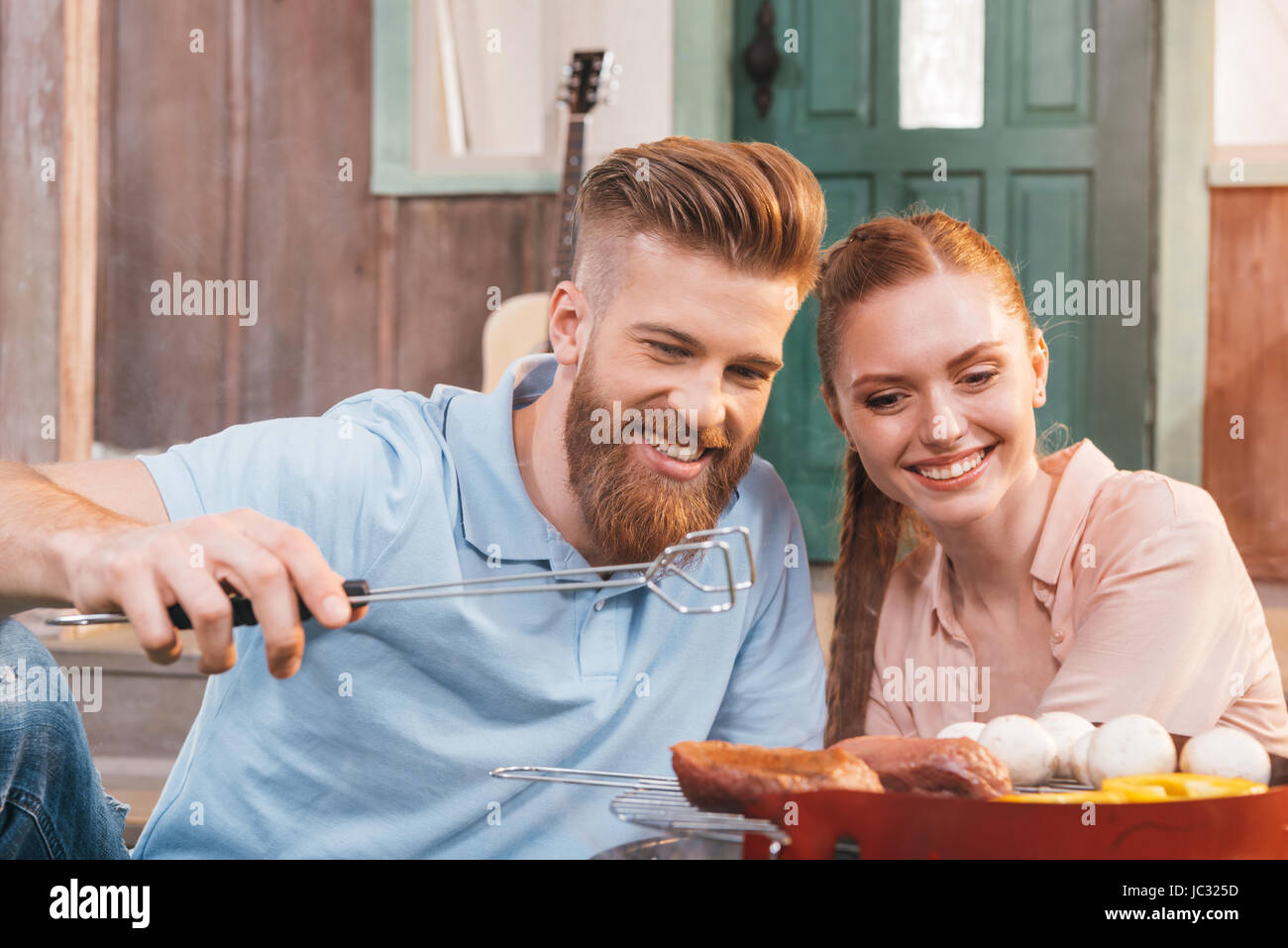 man and woman roasting meat and vegetables on barbecue grill Stock ...