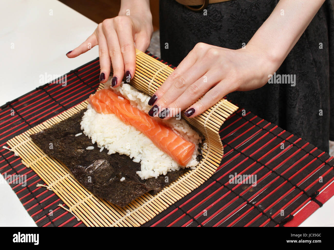 Woman using bamboo rolling mat for home made sushi Stock Photo - Alamy