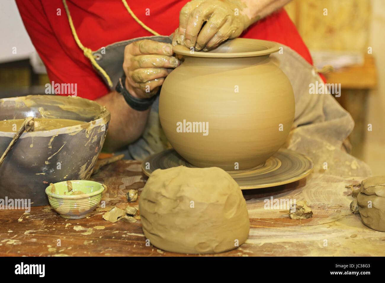 Potter making pot from clay at rotating table Stock Photo - Alamy