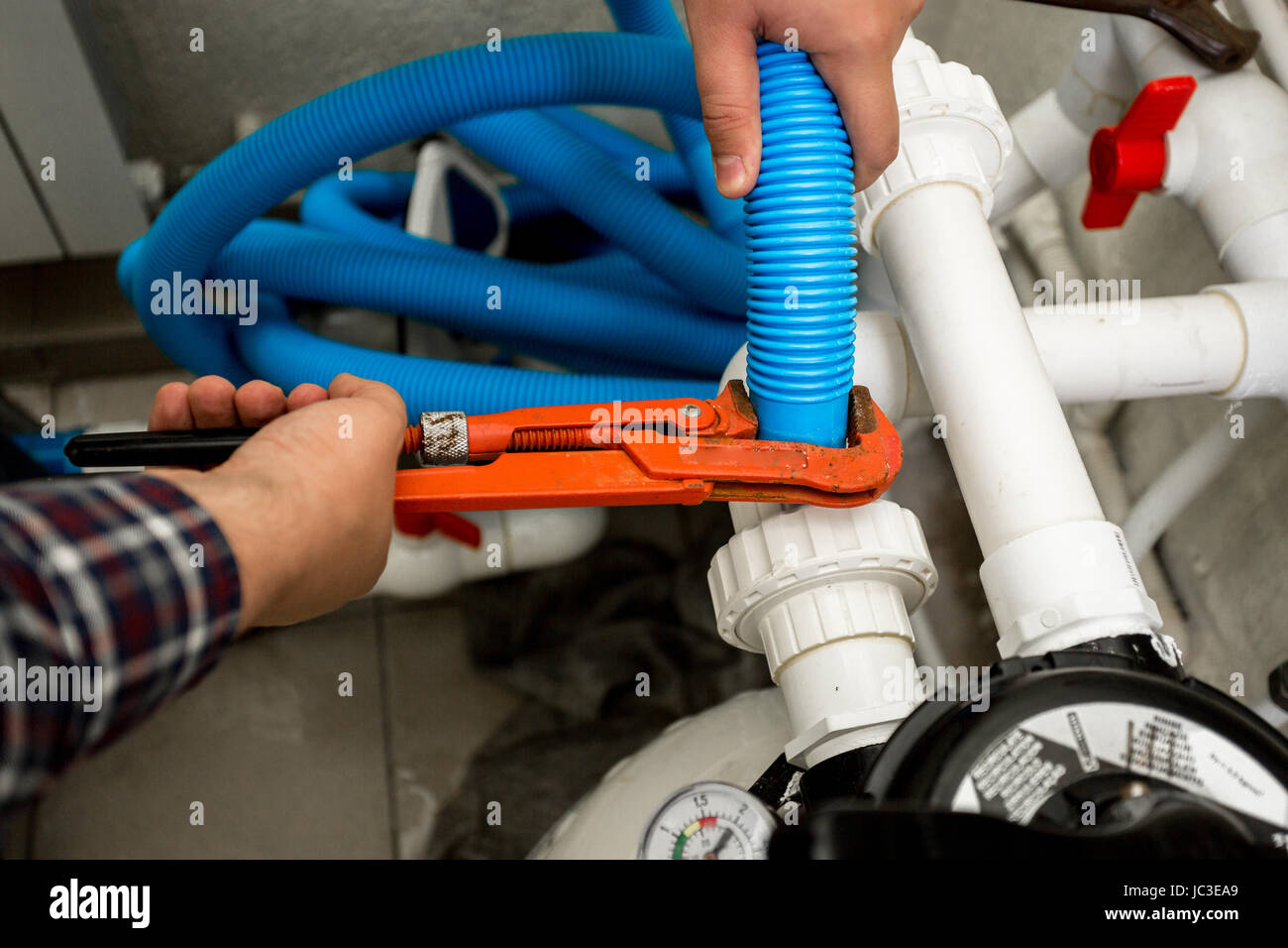 Closeup shot of plumber connecting two pipes with red pliers Stock ...