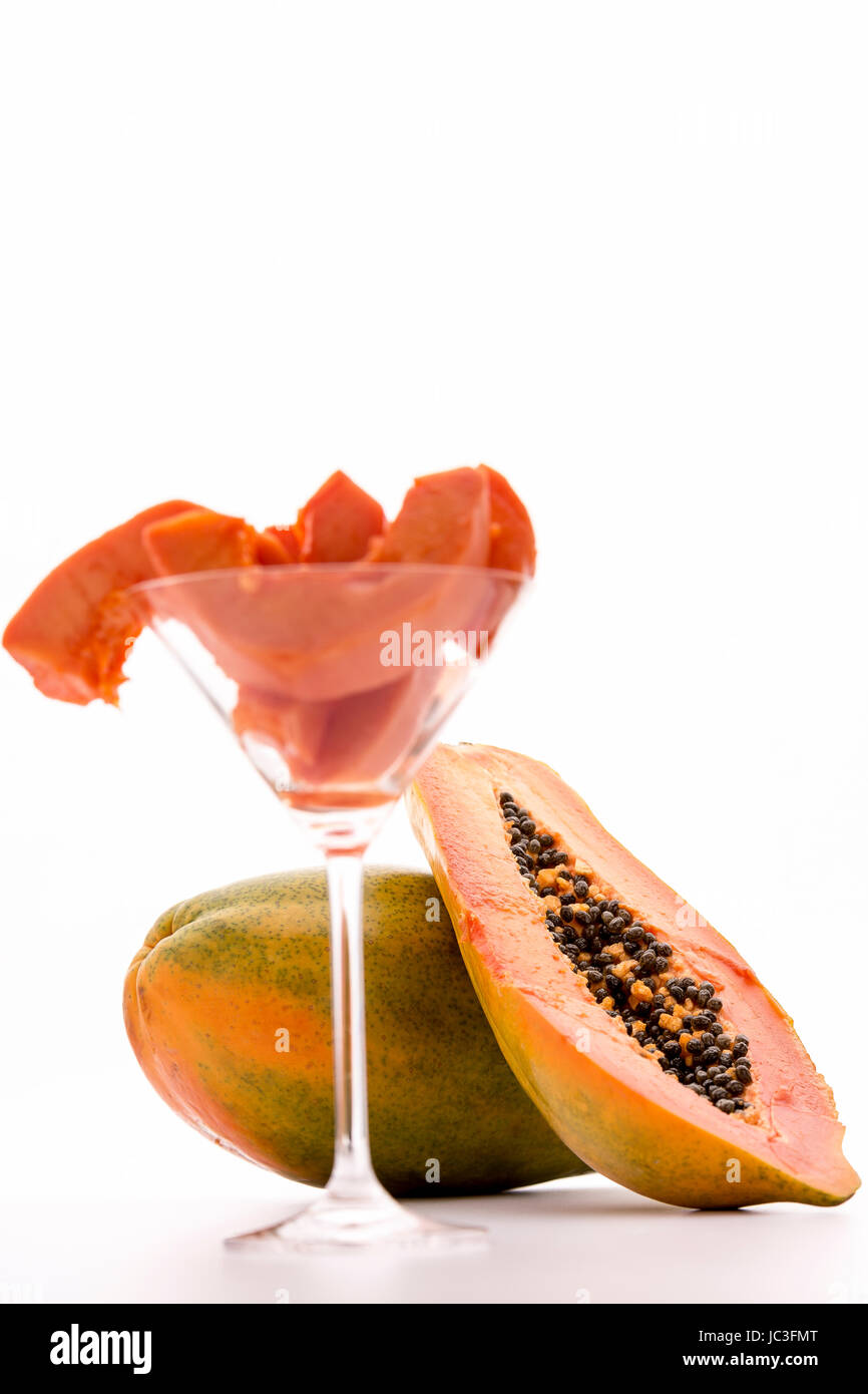 A halved papaya leaning against the globose body of an entire fruit ...