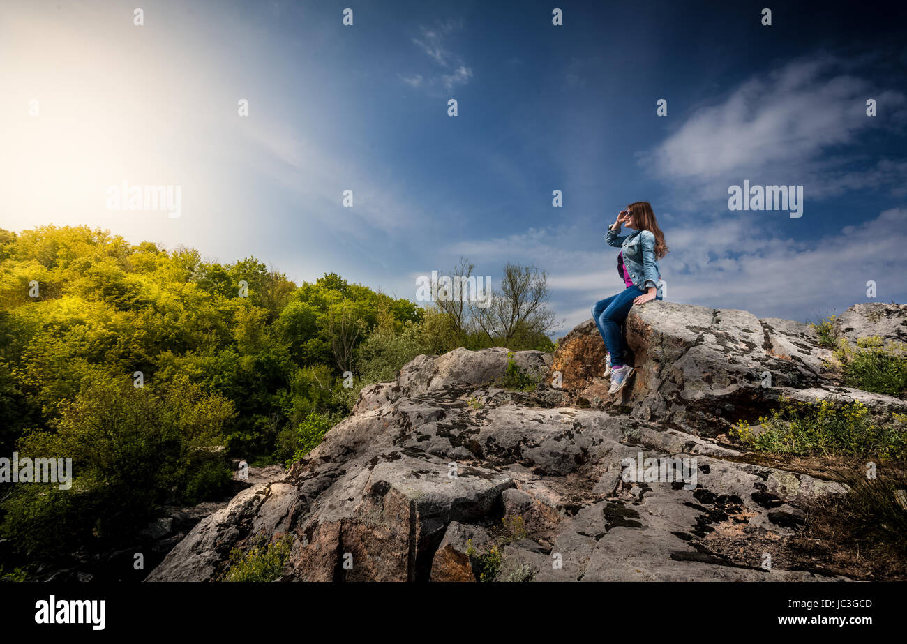 Photo of beautiful woman sitting on top of cliff and looking at sunset ...