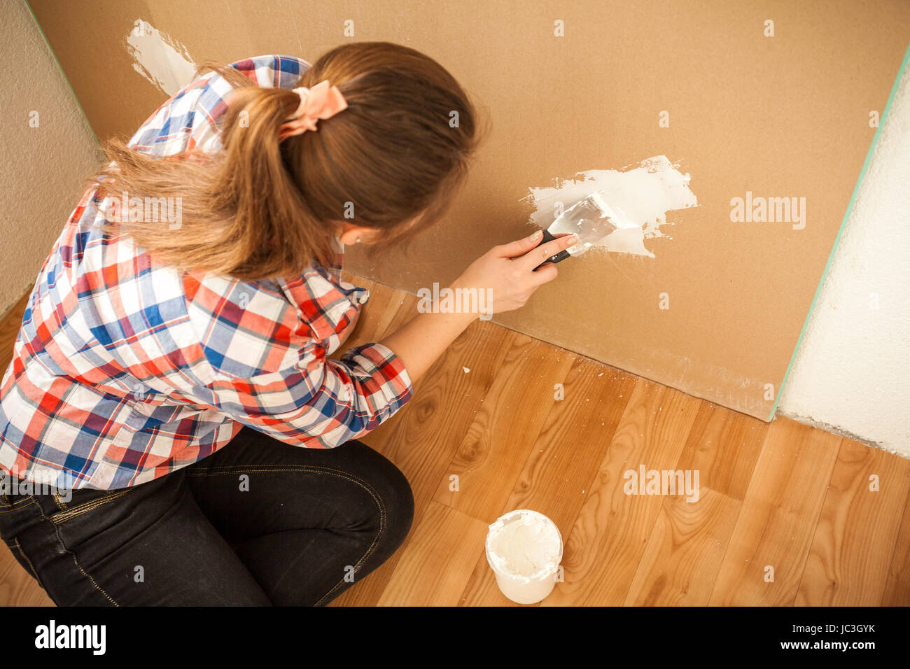 Brunette woman plastering wall at house Stock Photo - Alamy