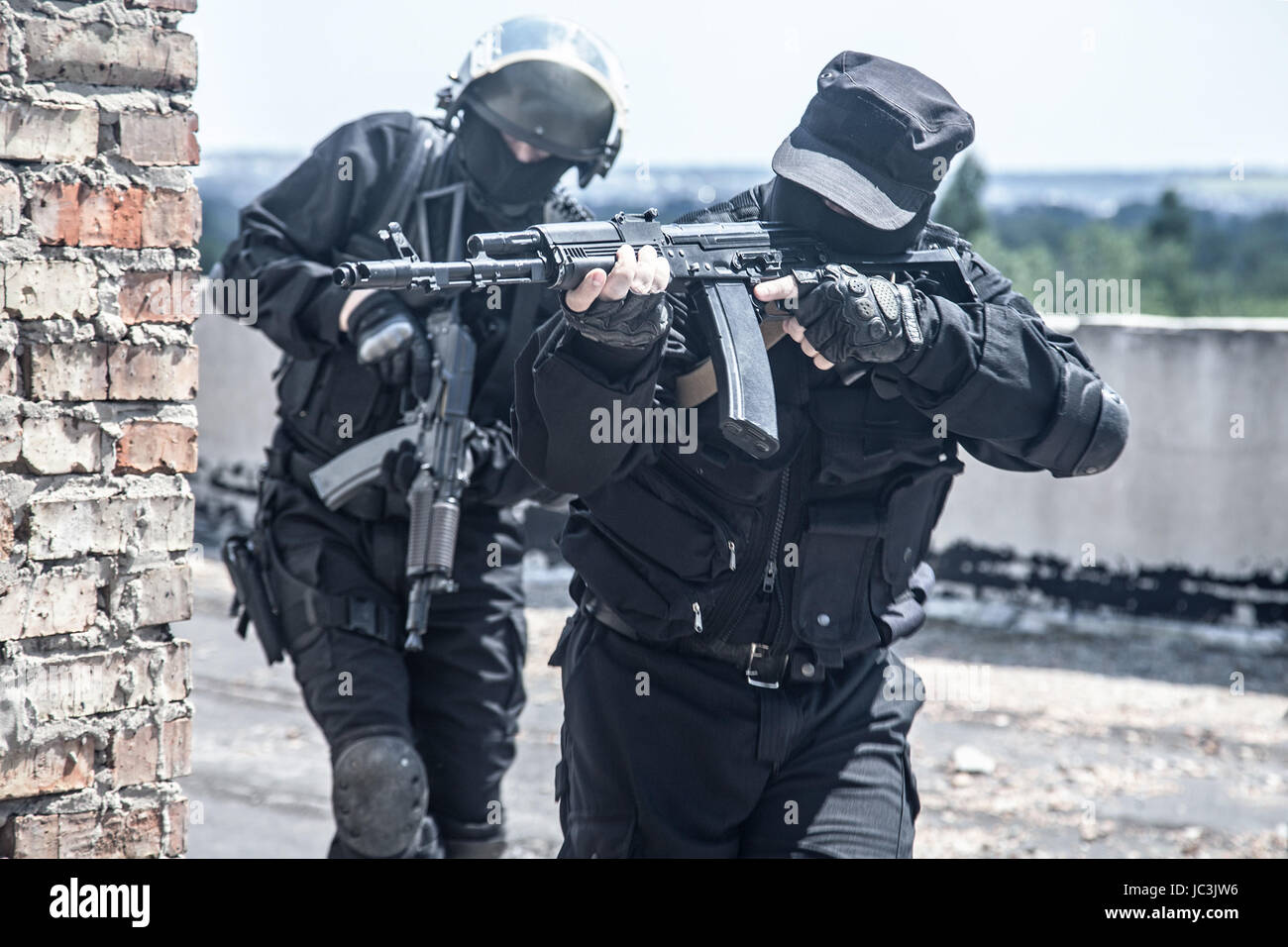 Two spec ops soldiers in black uniform in action Stock Photo - Alamy