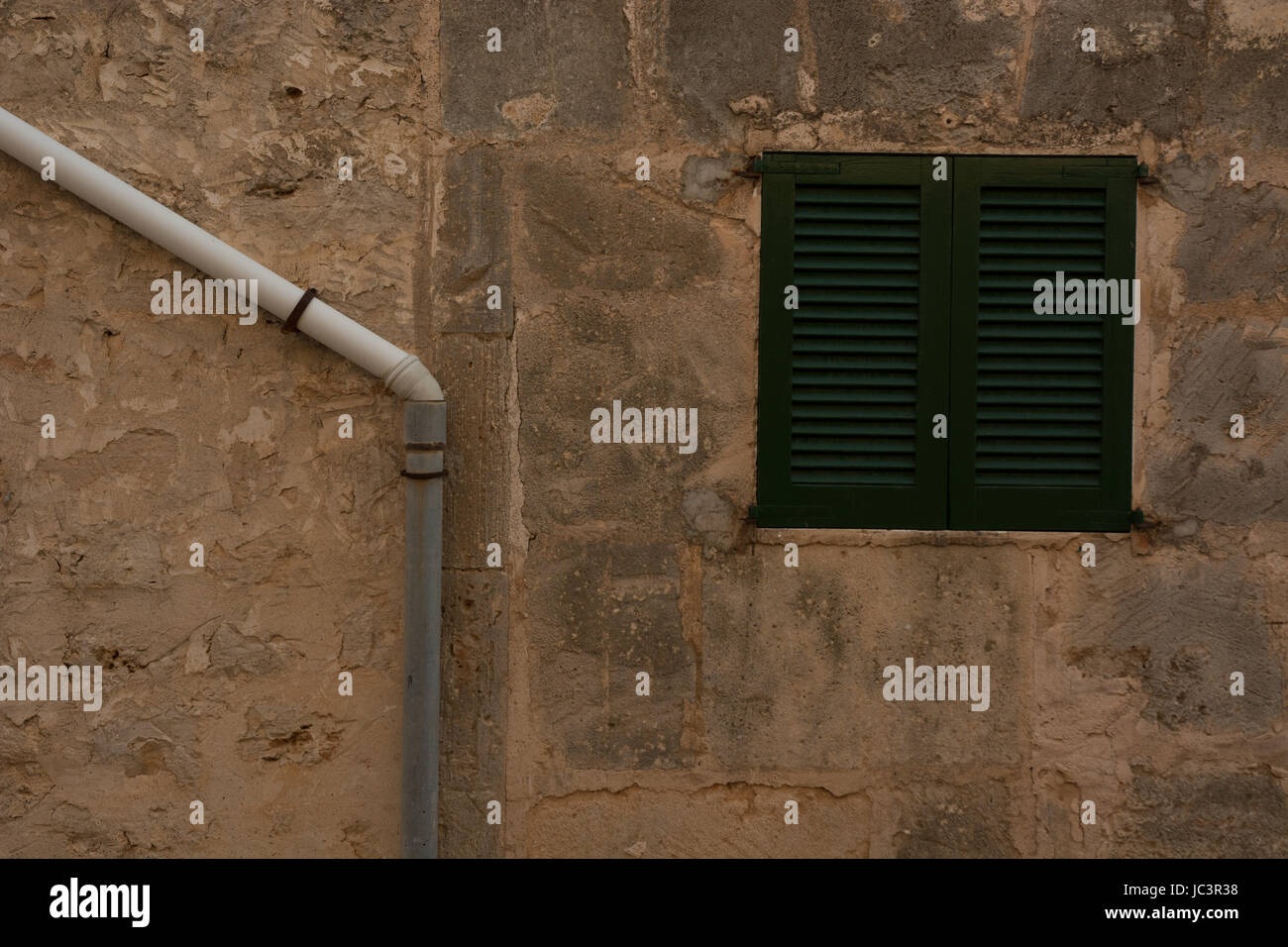 A green window shutter and a rain drain on a house front in Majorca ...