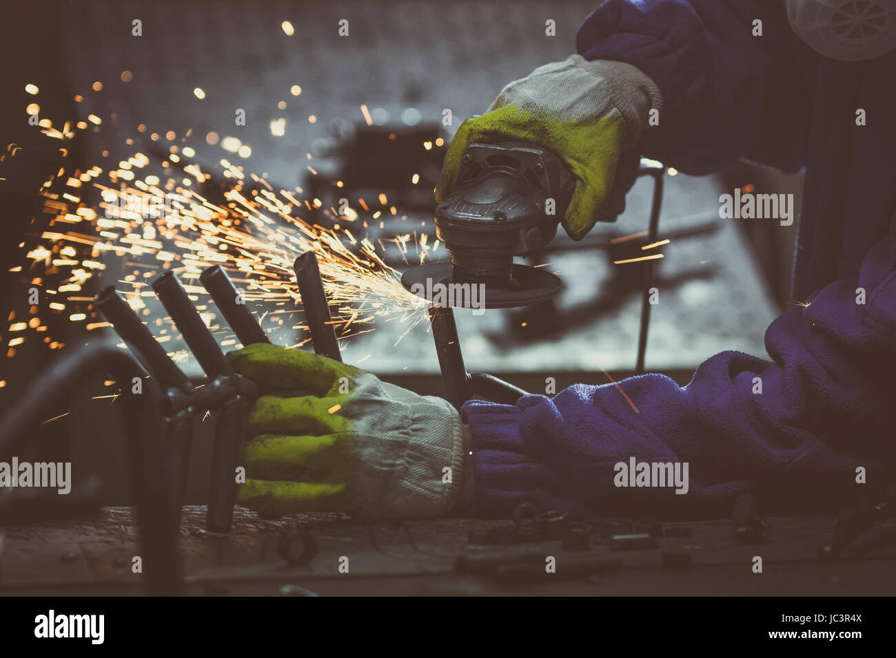 Worker grinding steel pipe with an electric disk grinder in the ...