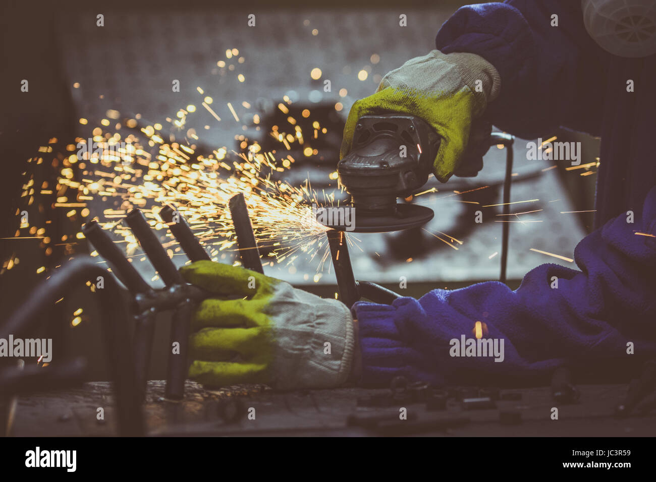 Worker grinding steel pipe with an electric disk grinder in the ...