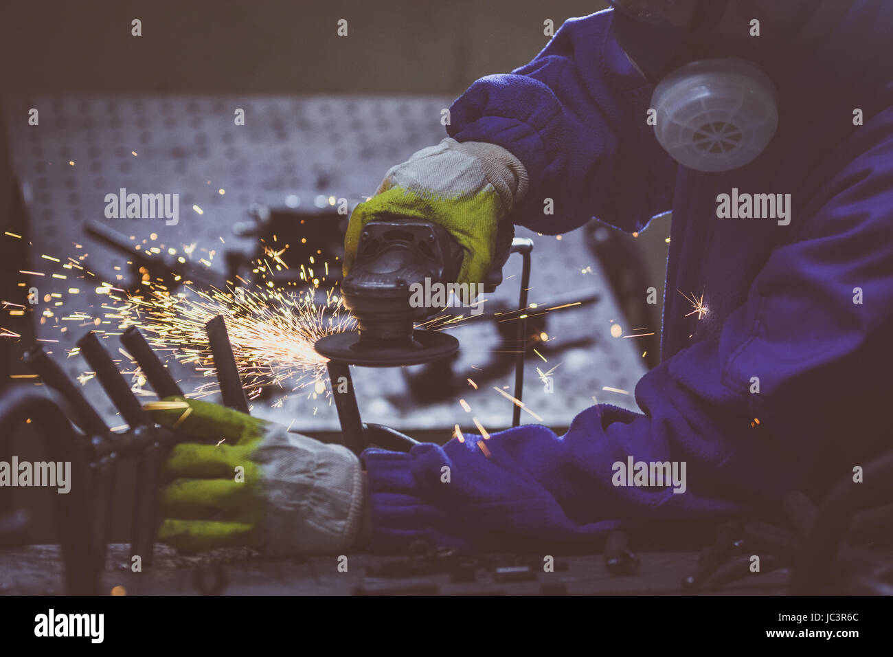 Worker grinding steel pipe with an electric disk grinder in the ...