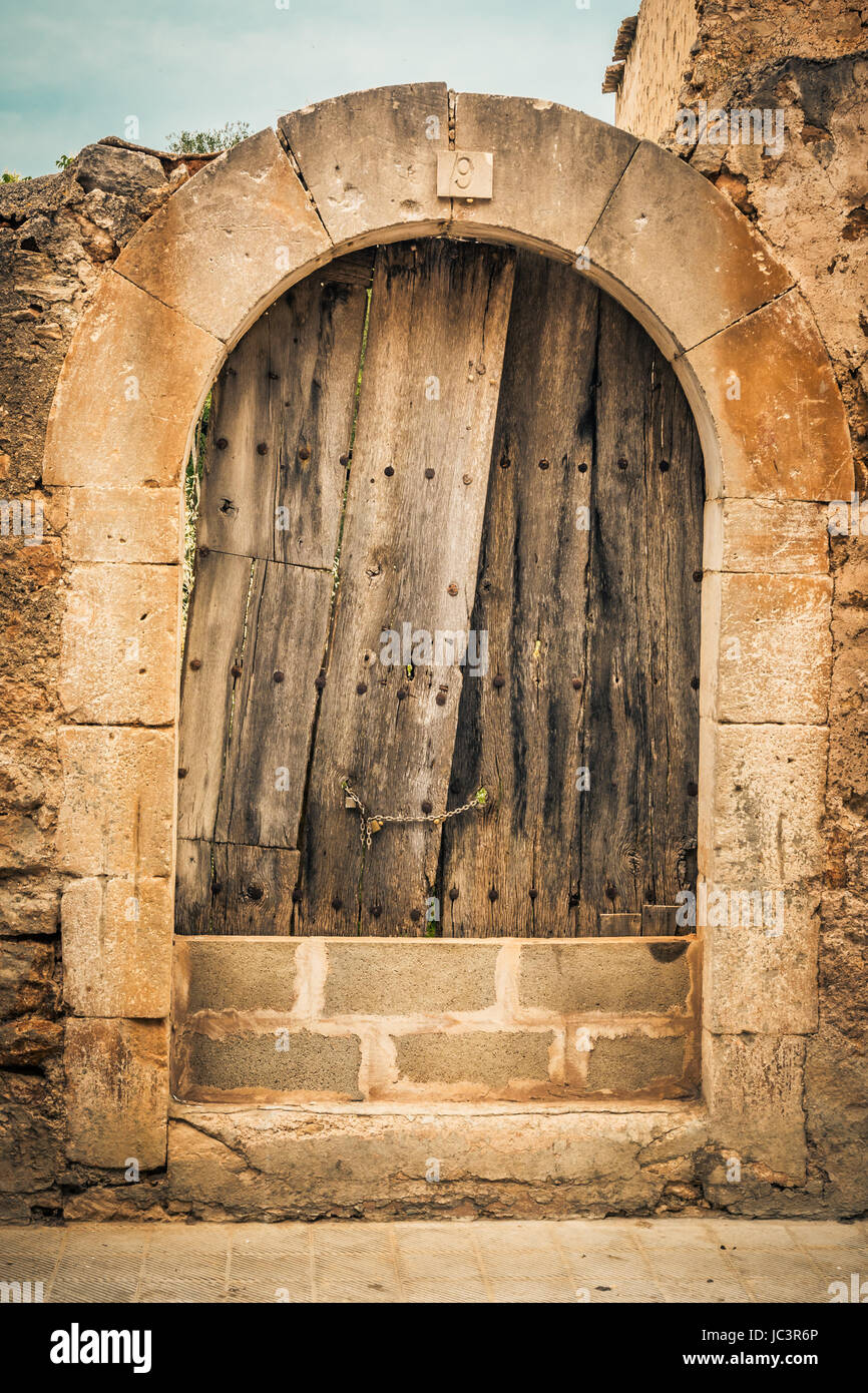 Destroyed wooden door in an old archway Stock Photo - Alamy