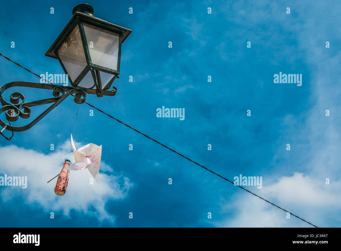 A toy wind wheel hanging under an old street light Stock Photo - Alamy