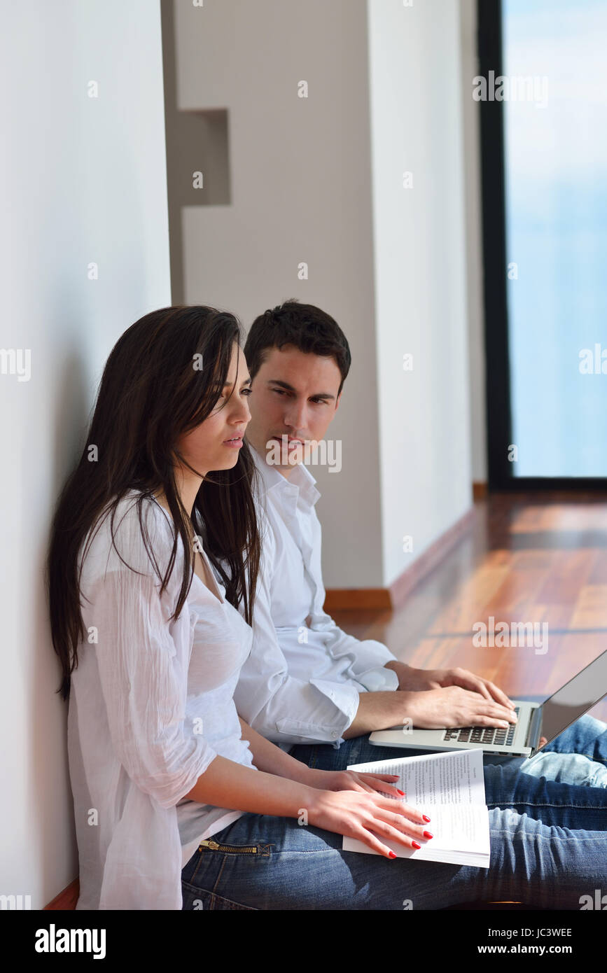 happy young relaxed couple working on laptop computer at modern home ...