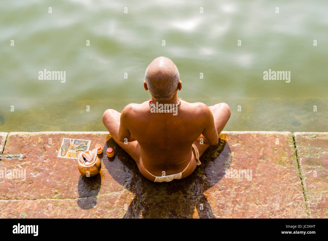 A pilgrim is praying, meditating at the holy river Ganges at ...