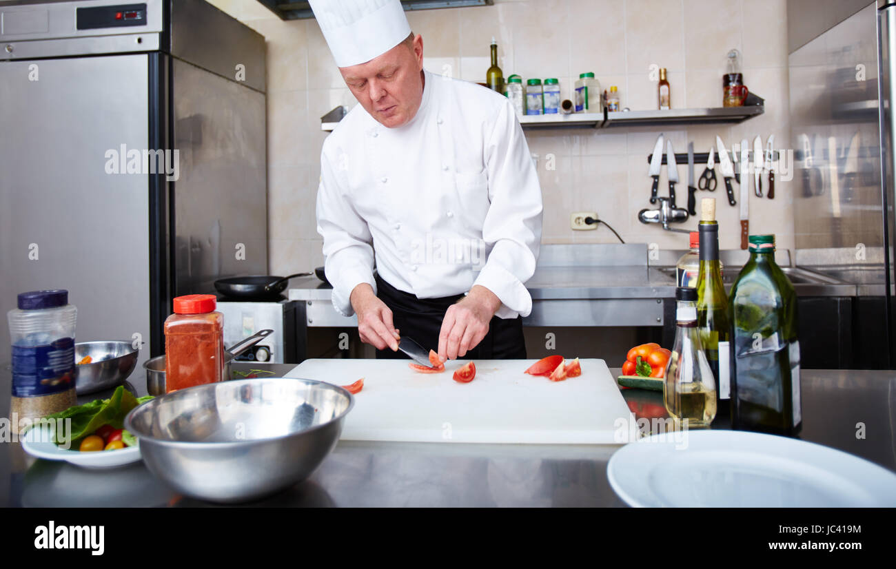 Chef cutting tomatoes at the kitchen Stock Photo - Alamy