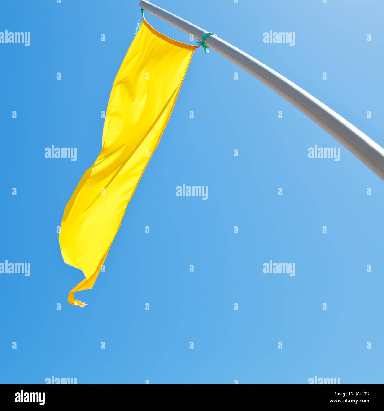 warning sign - yellow flag with blue sky background Stock Photo - Alamy