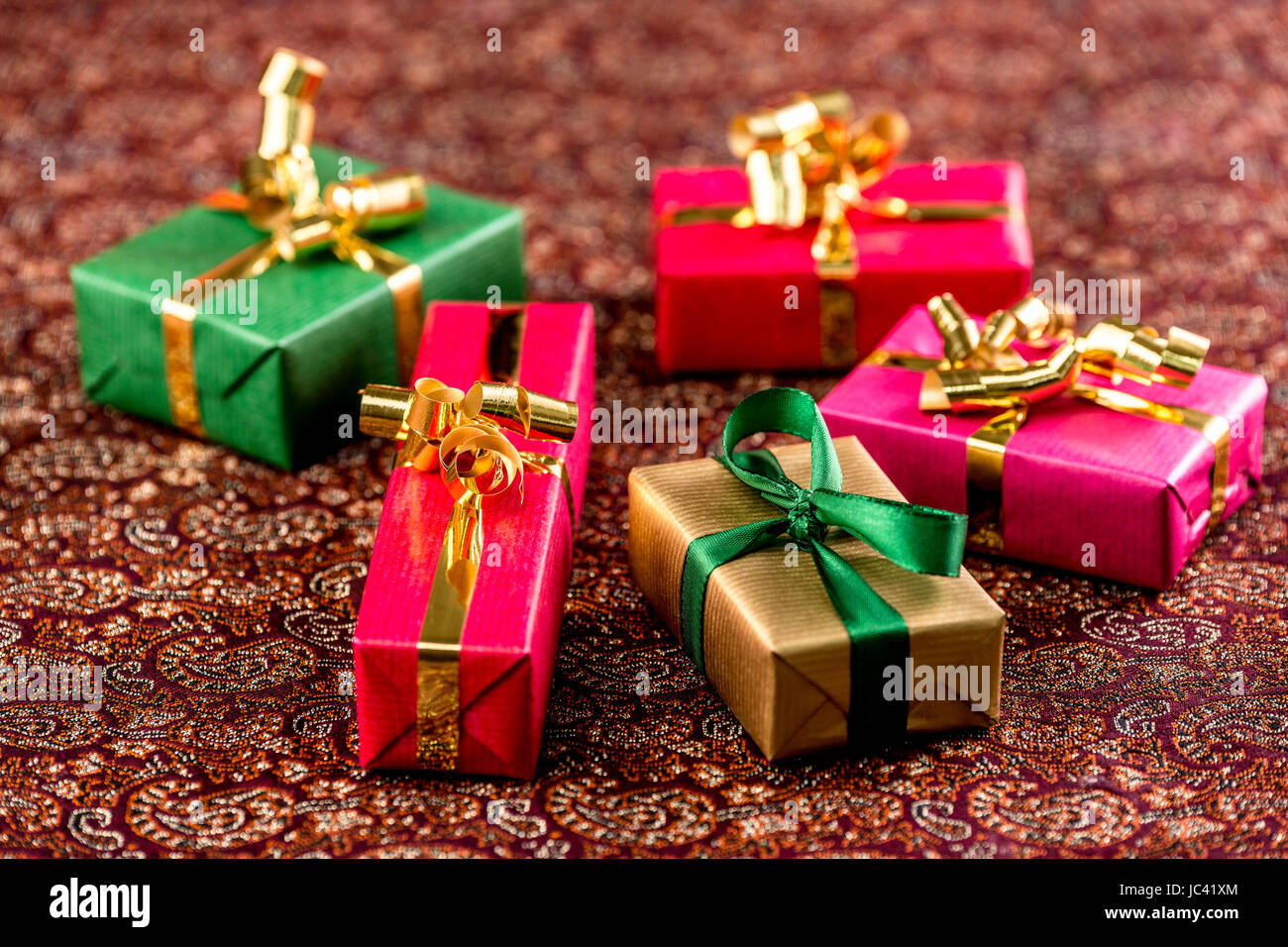 Five small gifts wrapped in plain colors. Red, green, gold and magenta ...