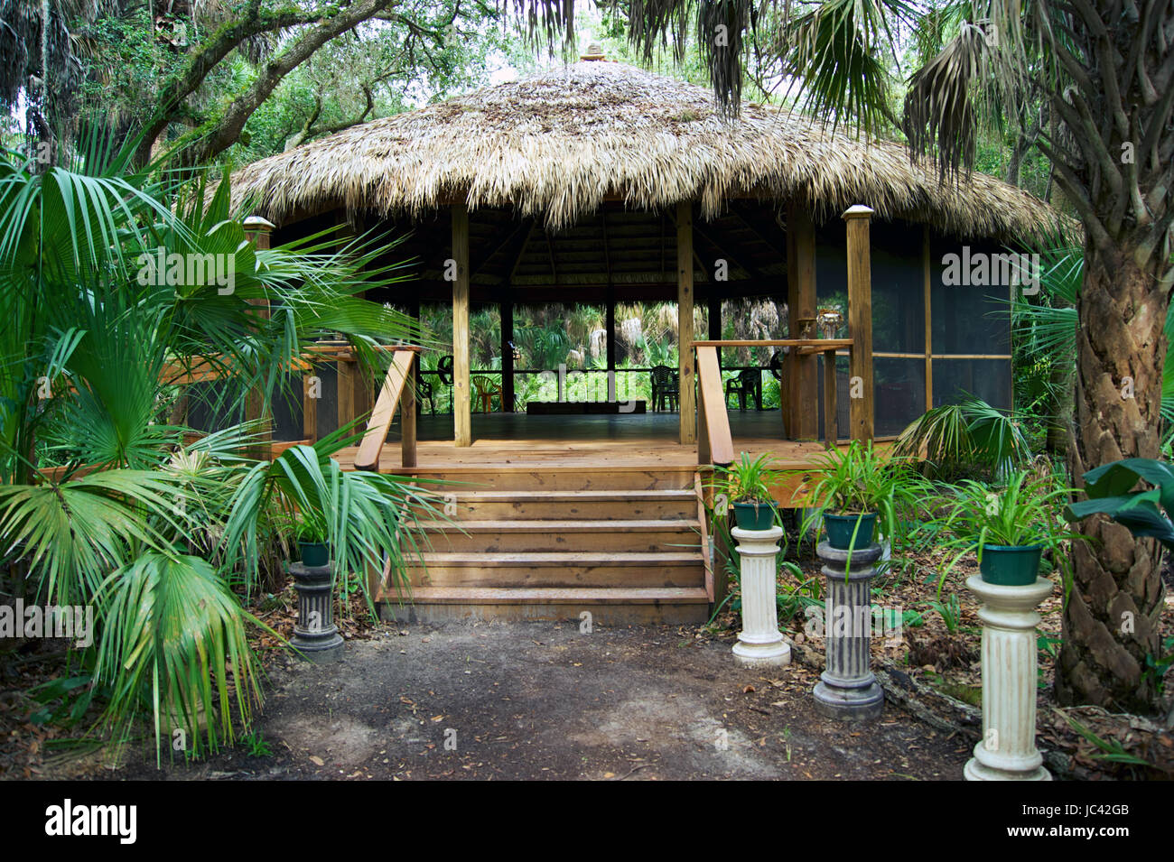 Looking up the path to a thatched roofed screened building in park in ...