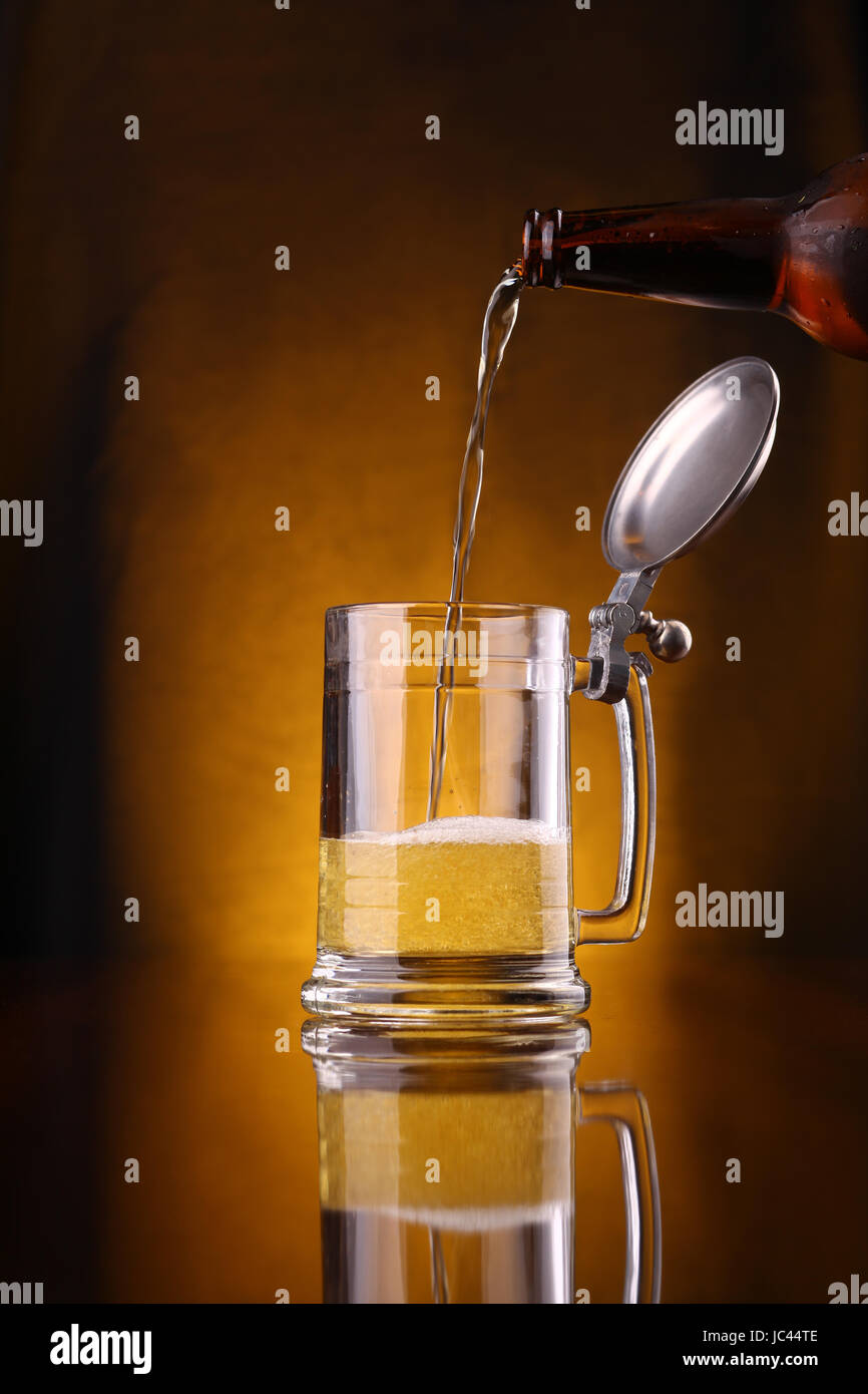 Pouring light beer from a bottle into a mug Stock Photo - Alamy