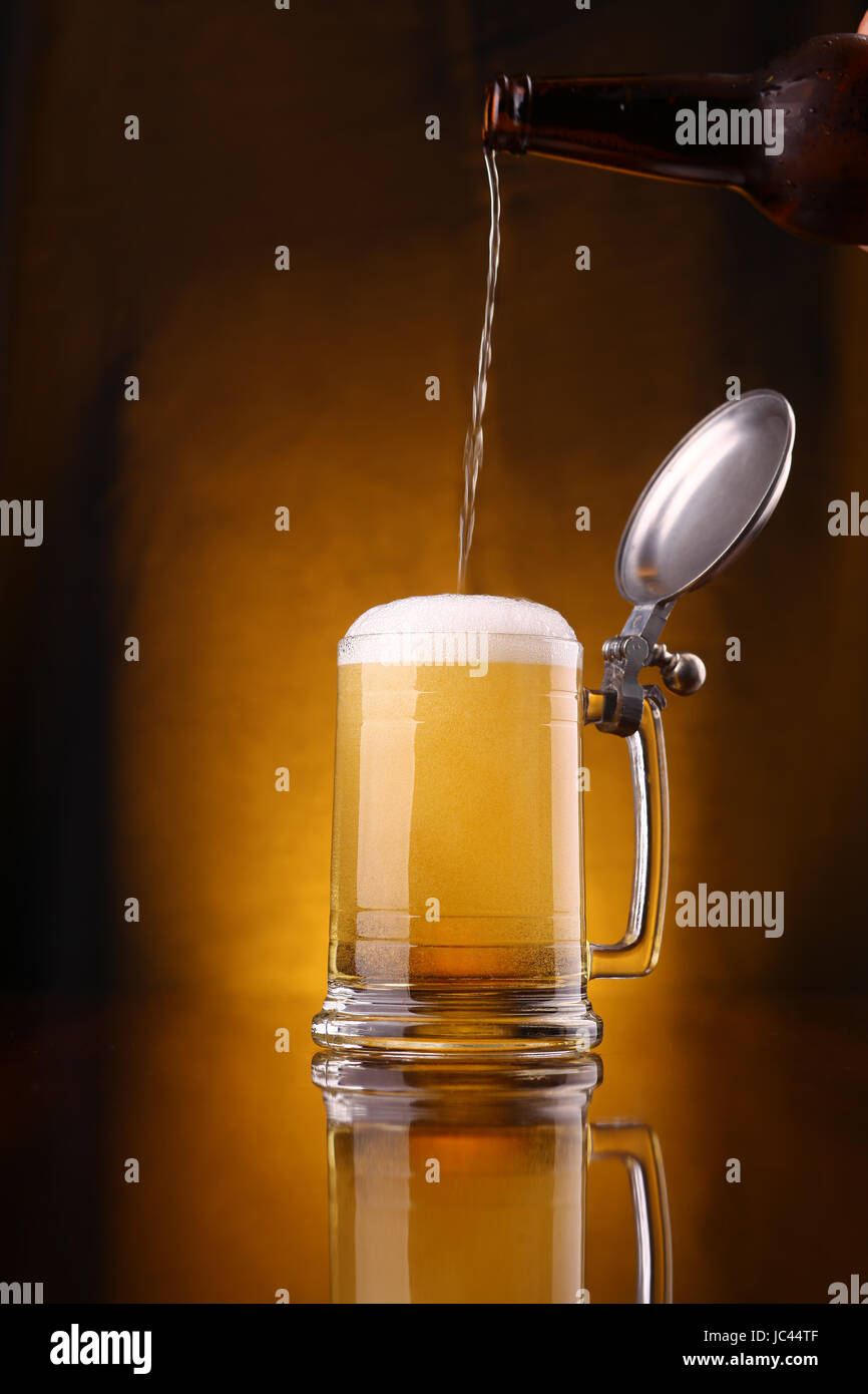 Pouring light beer from a bottle into a mug Stock Photo - Alamy