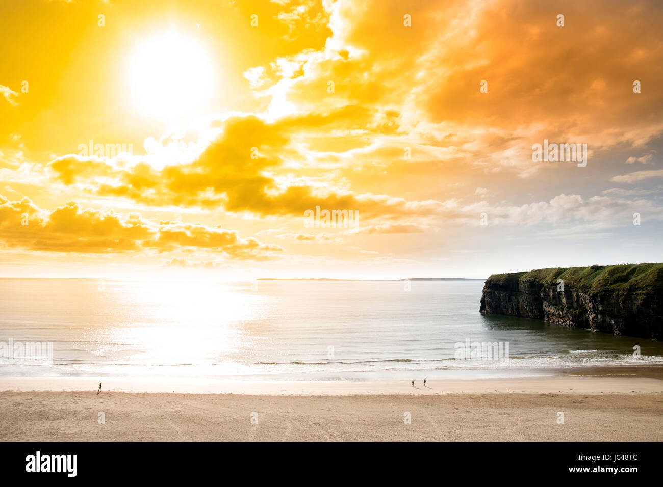 tourists walking the Ballybunion beach near cliffs in county Kerry ...
