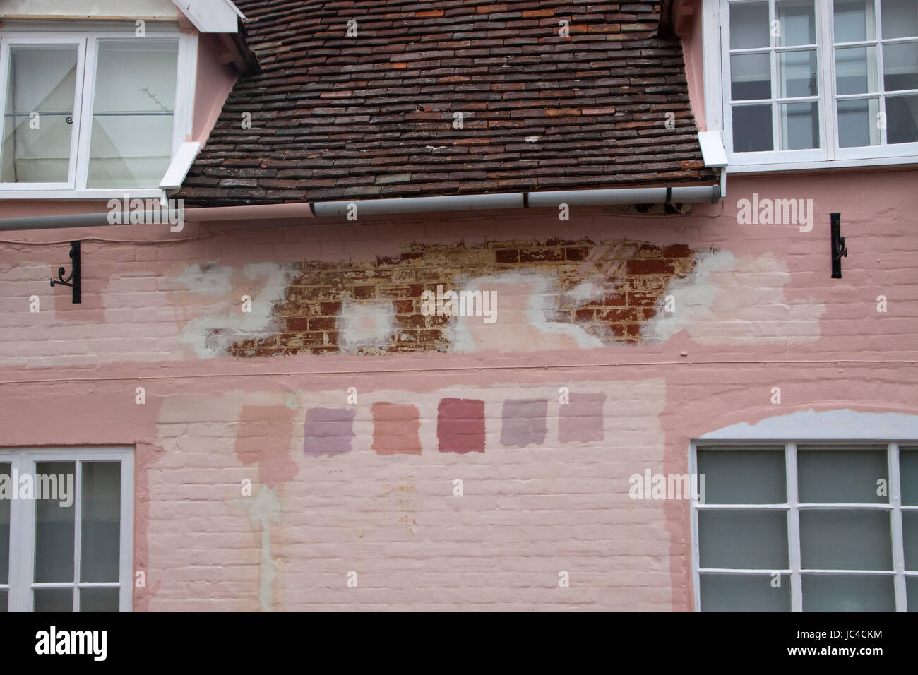 Pink Suffolk house wall prepared for painting with colour/color test ...