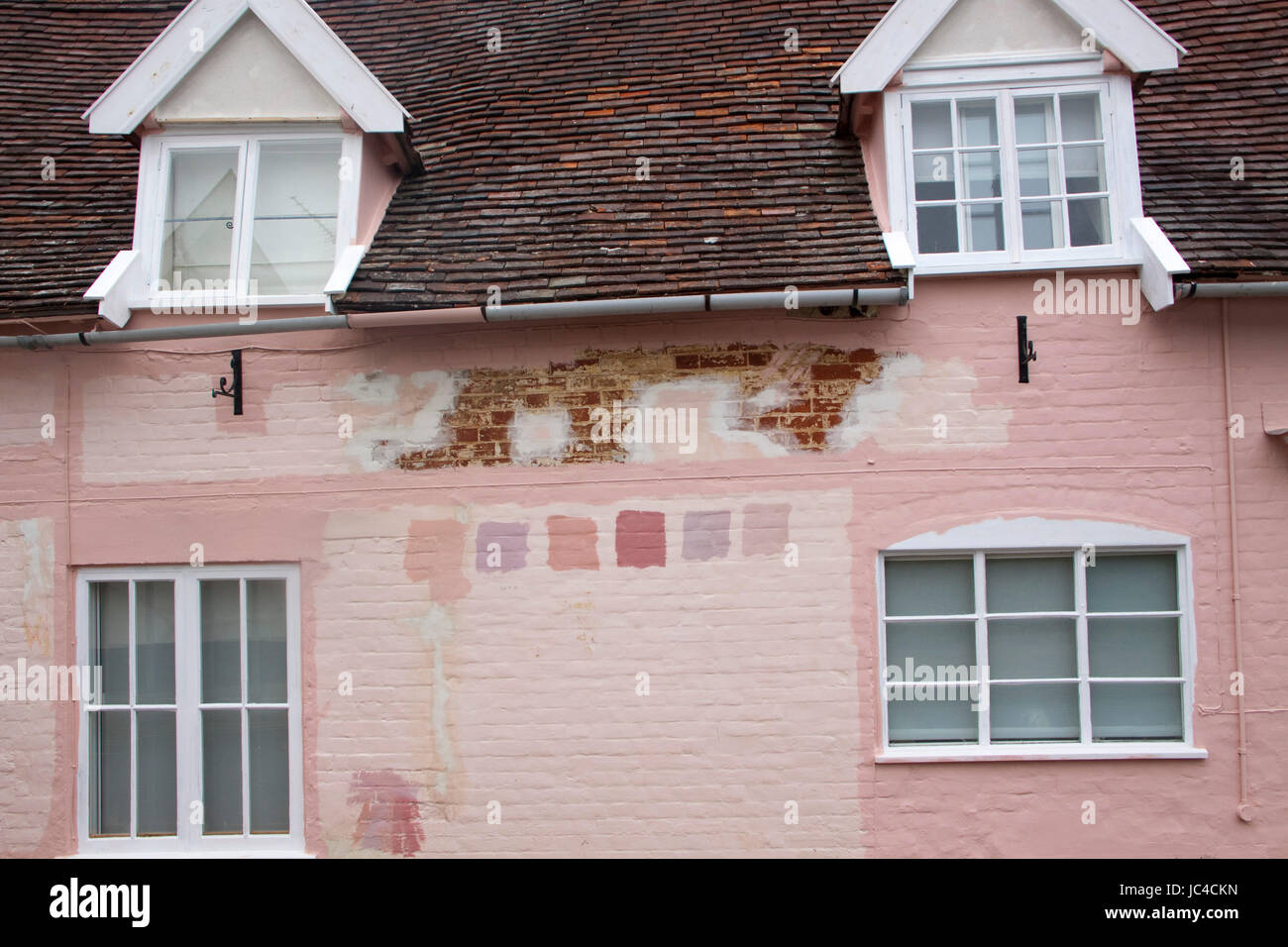 Pink Suffolk house wall prepared for painting with colour/color test ...