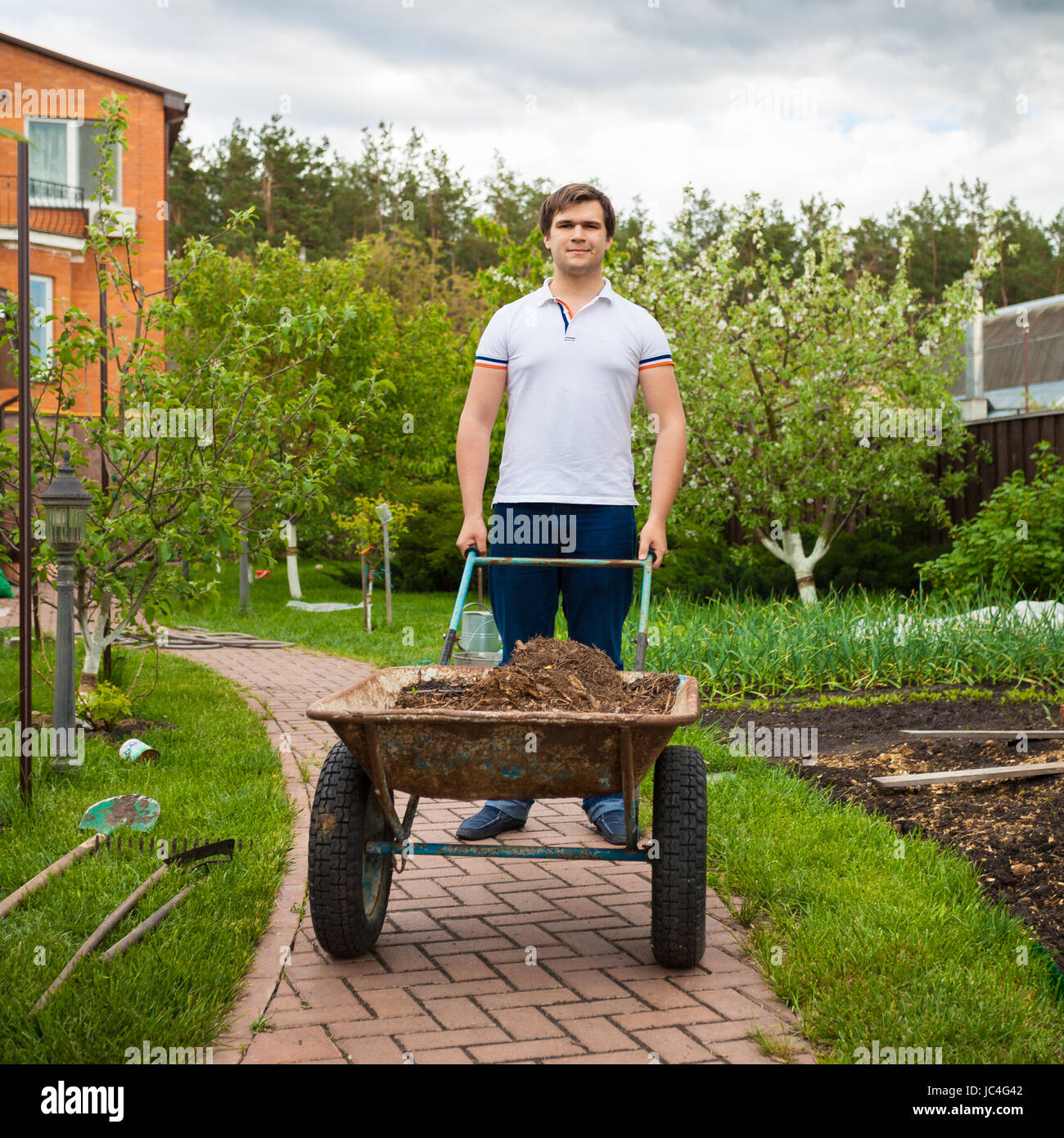 Photo of young man carrying garden wheelbarrow Stock Photo - Alamy