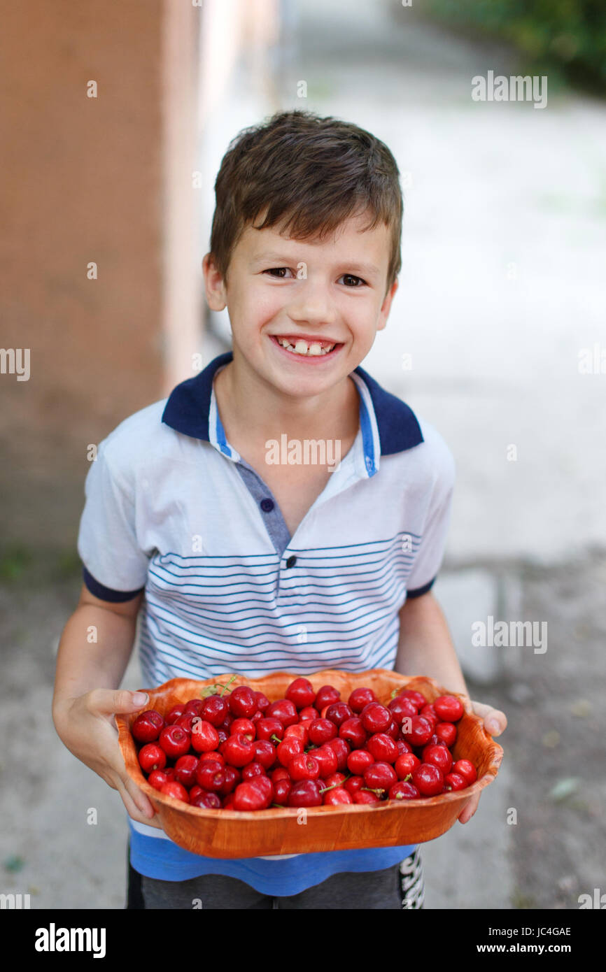 Happy little boy holding bowl of cherries Stock Photo - Alamy