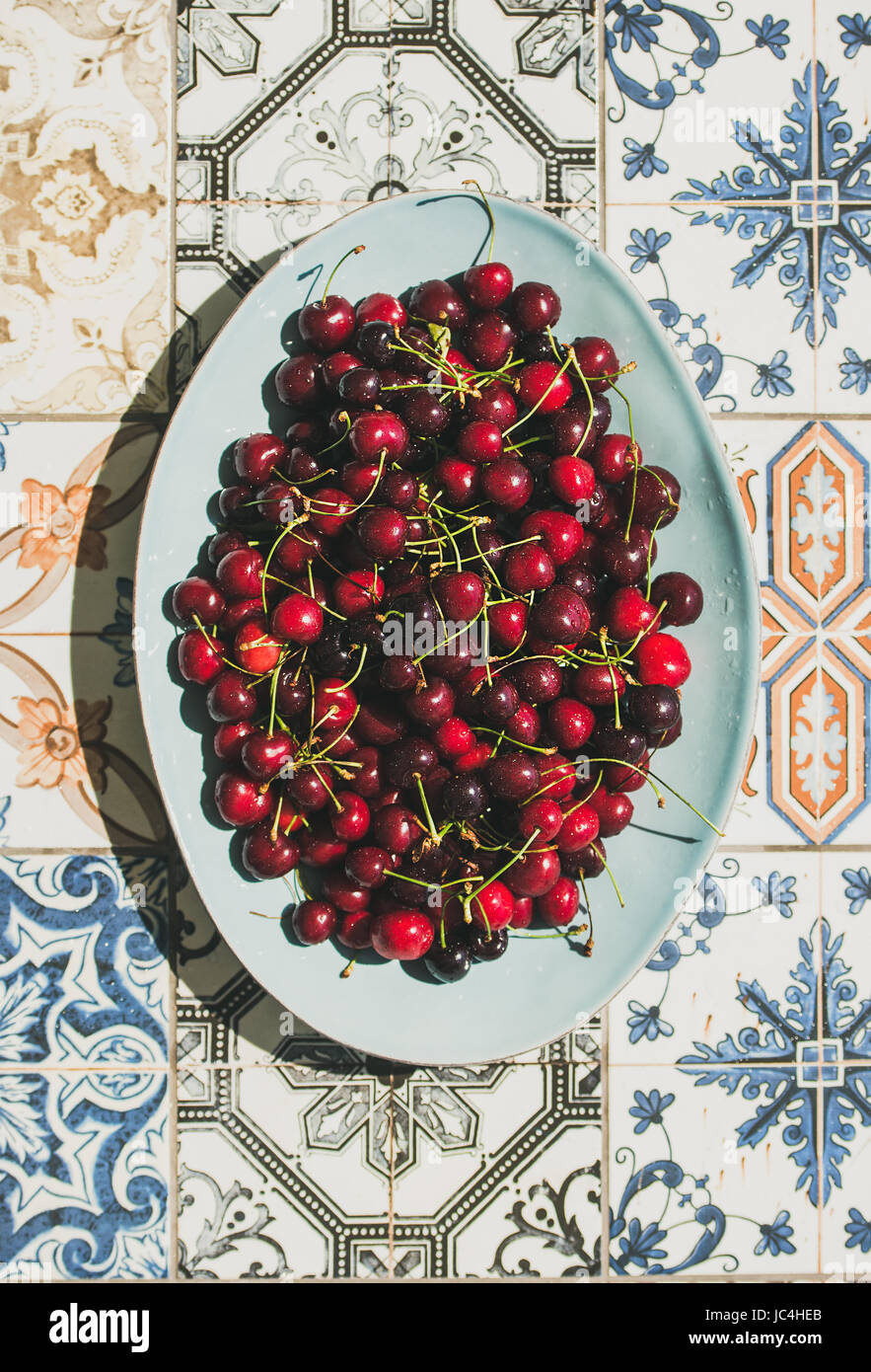Fresh sweet cherries over oriental ceramic tiles background, top view ...