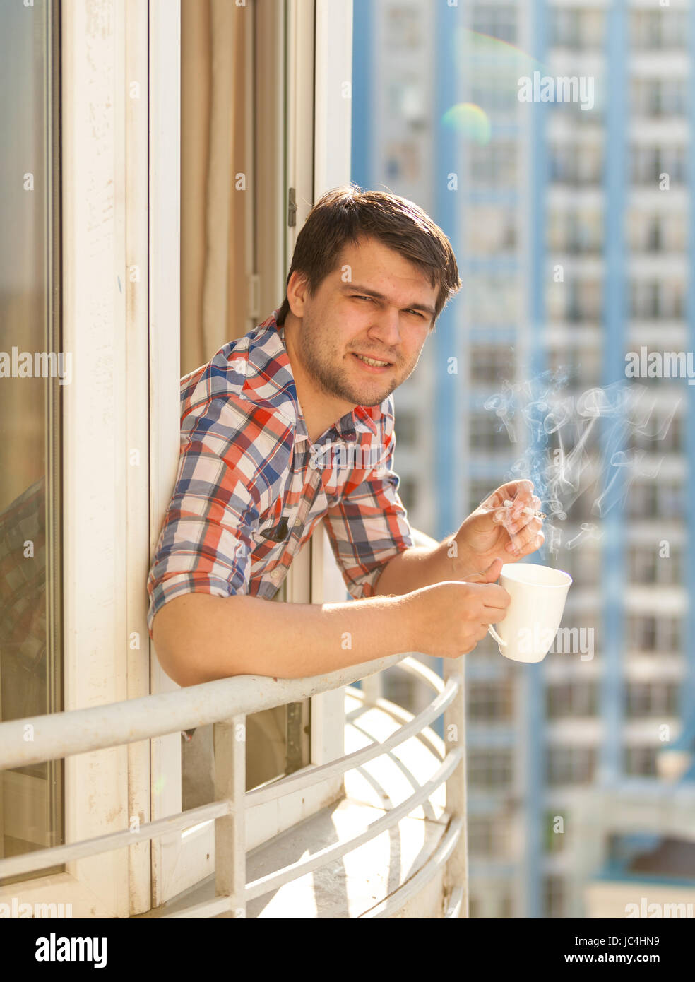 Closeup portrait of hipster guy drinking coffee on balcony Stock Photo ...