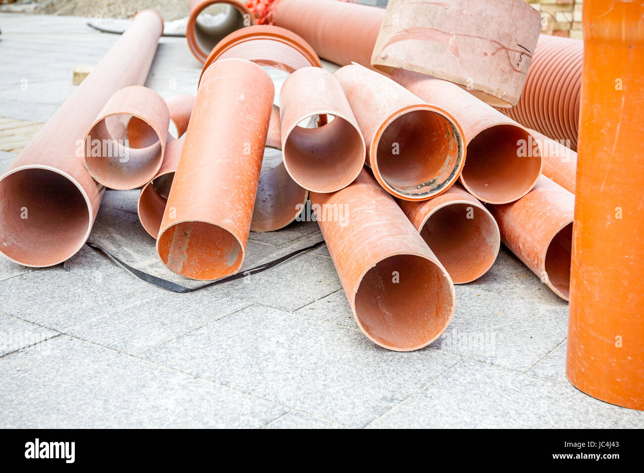 Sewer pipes waiting to be placed into the ditch at construction site ...