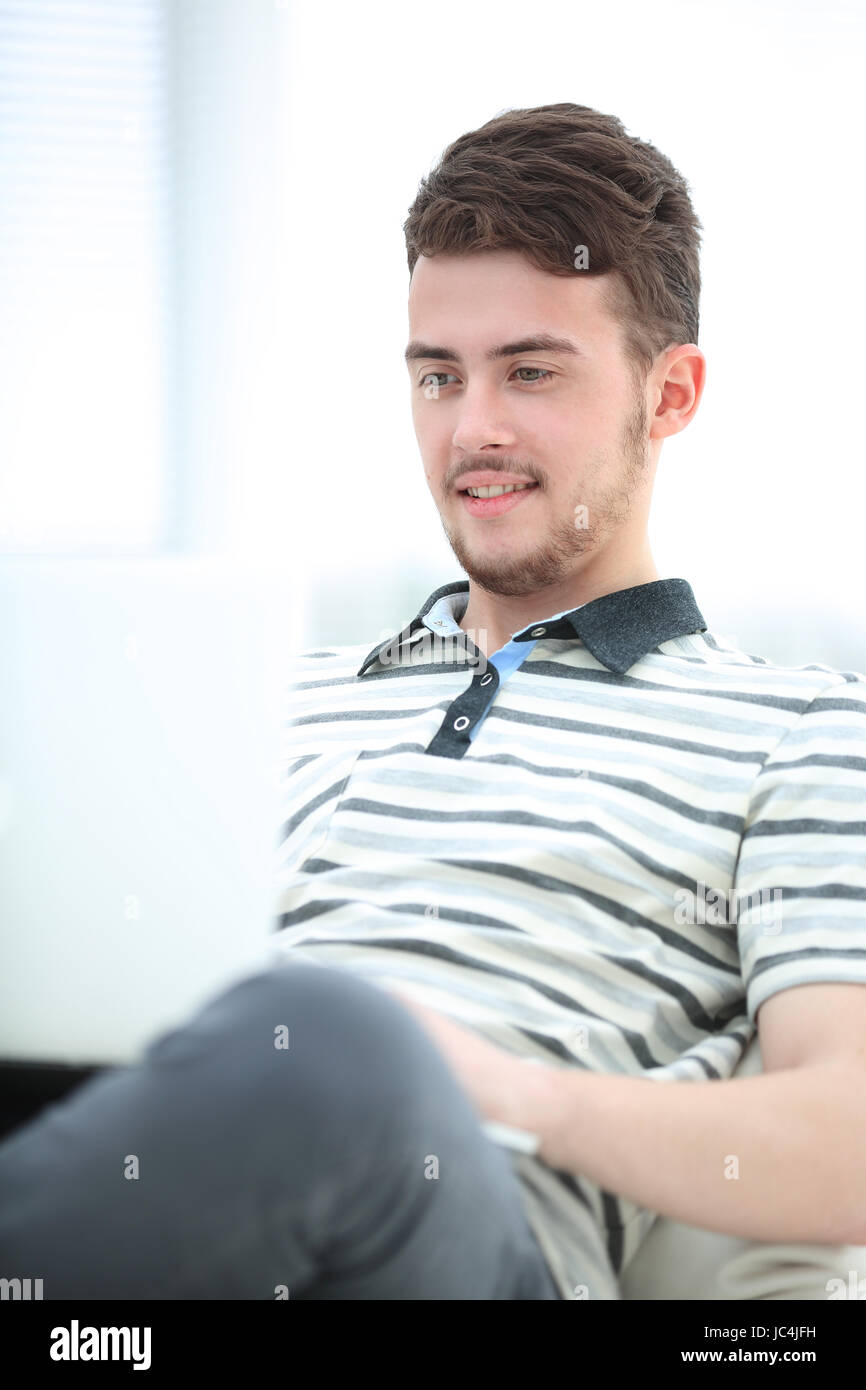 Happy young man using his laptop in bright living room Stock Photo - Alamy