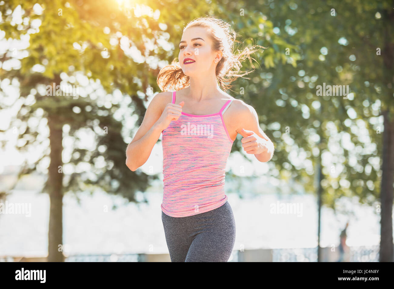 Pretty sporty woman jogging at park in sunrise light Stock Photo - Alamy