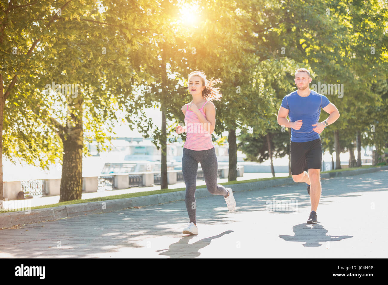 The sporty woman and man jogging at park in sunrise light Stock Photo ...