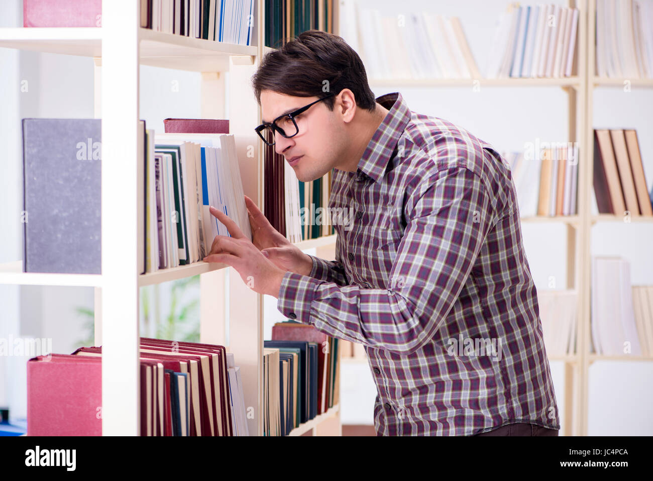 Young student looking for books in college library Stock Photo - Alamy