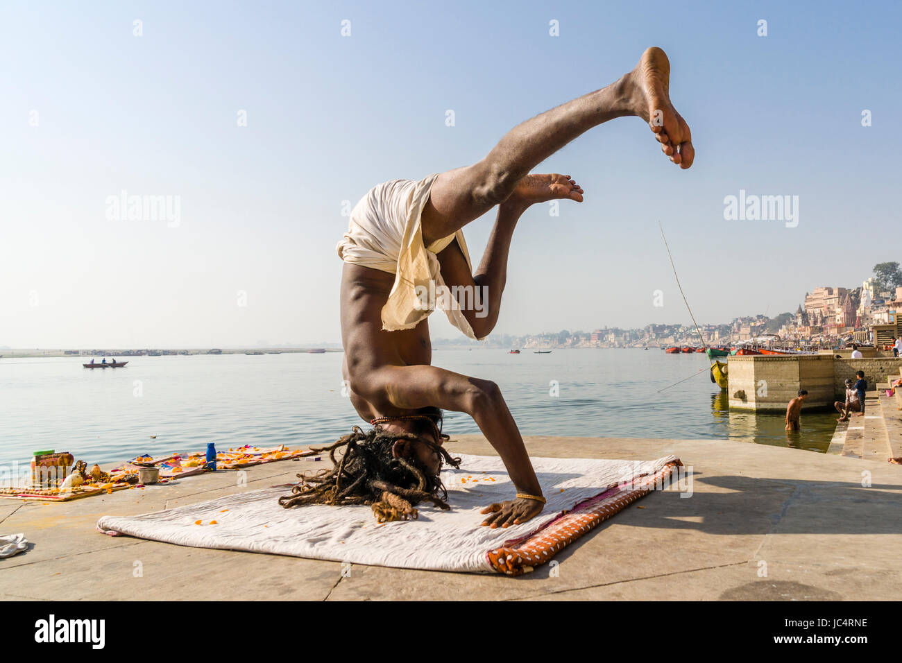A Sadhu, holy man, is practising yoga asana on a platform at the holy river Ganges at Meer Ghat ...