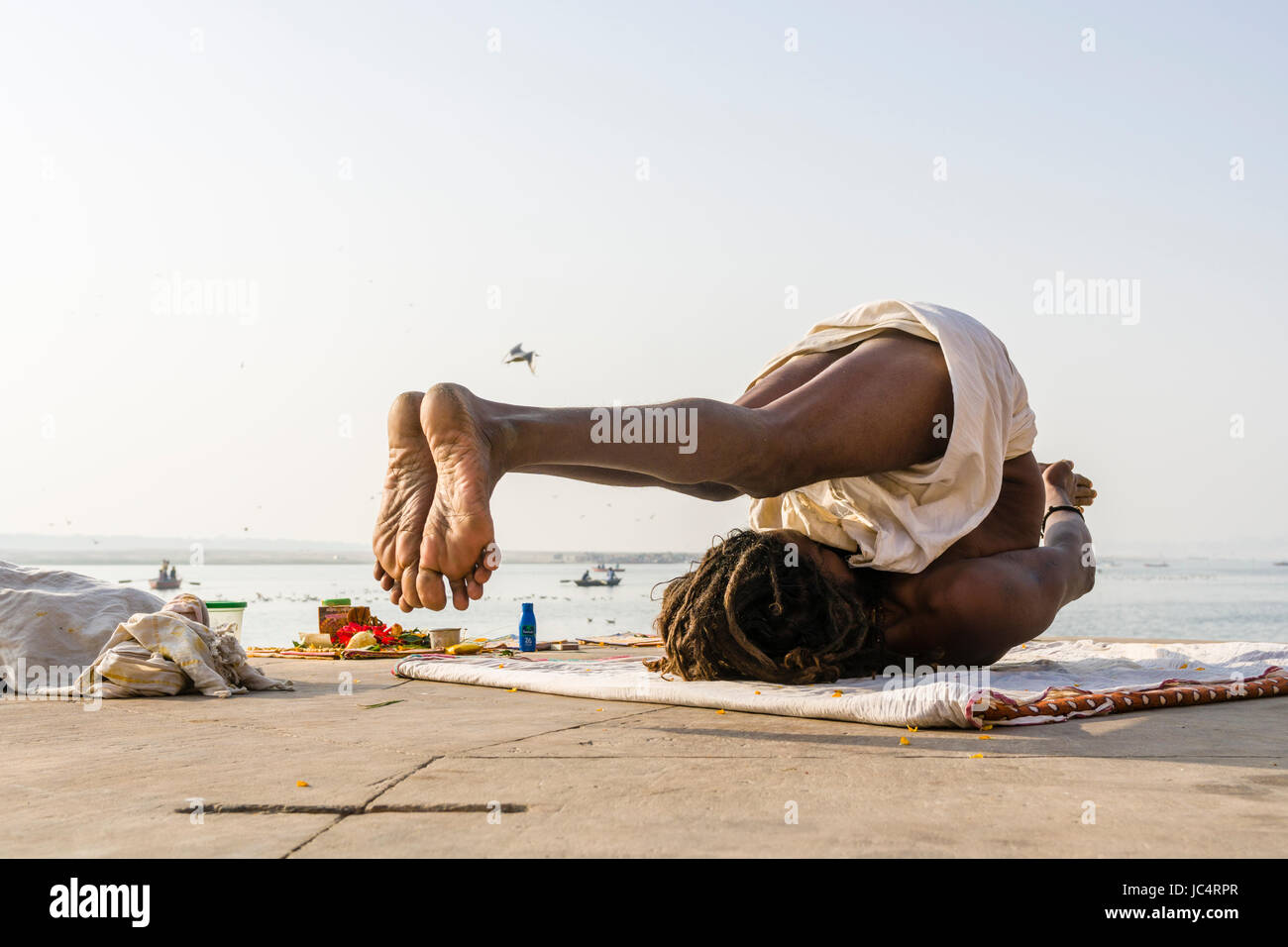 A Sadhu, holy man, is practising yoga asana on a platform at the holy ...