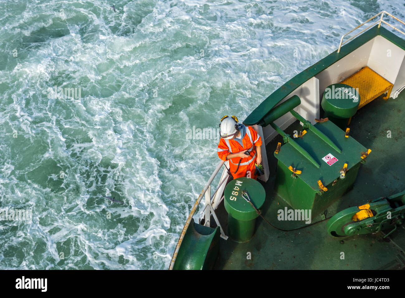 Female crew member with radio / walkie-talkie in orange overall and ...