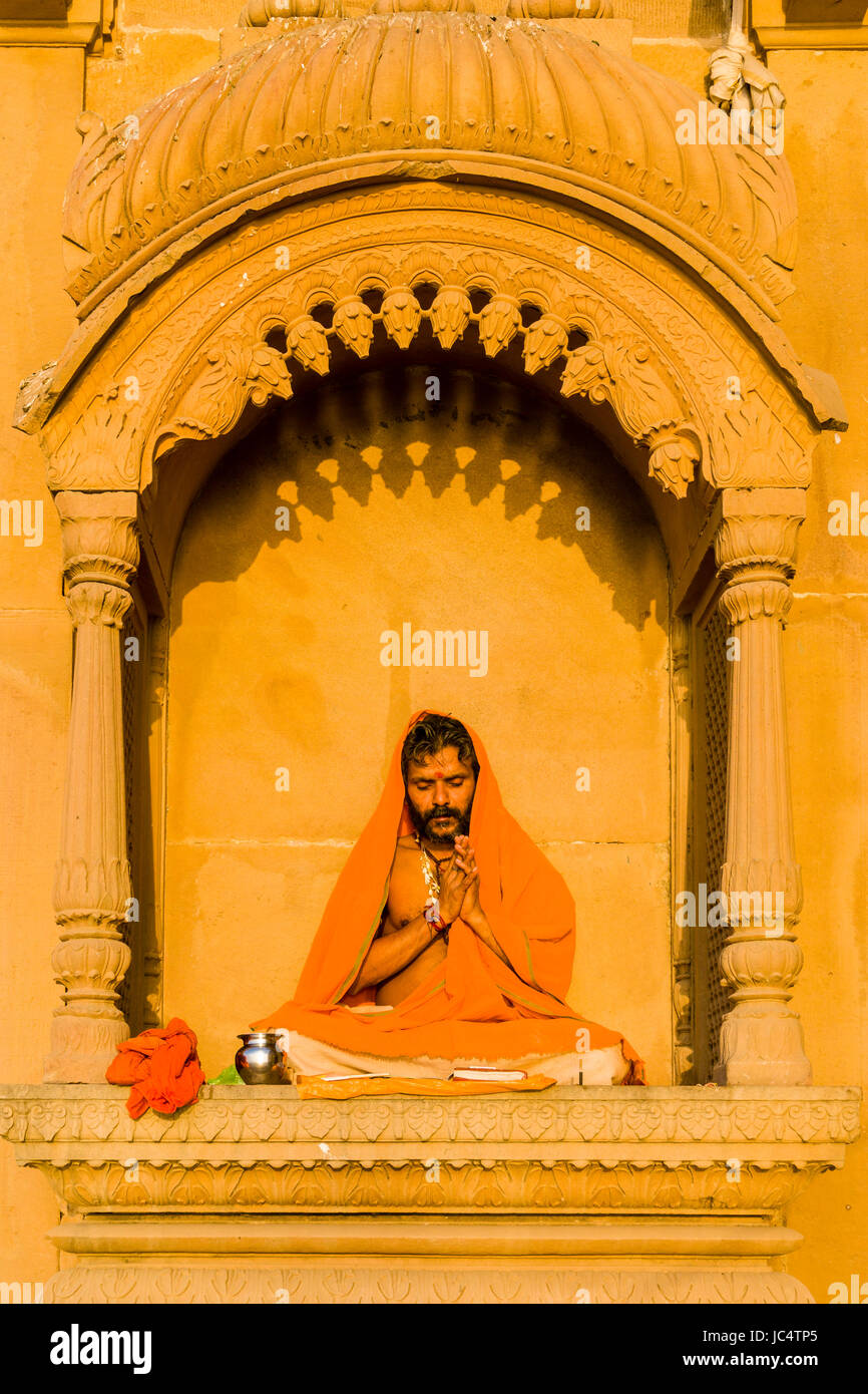 A priest, Brahmin, is sitting and praying on a balcony at the holy ...