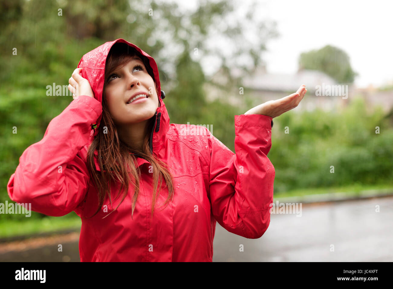 Beautiful woman in raincoat checking for rain Stock Photo - Alamy