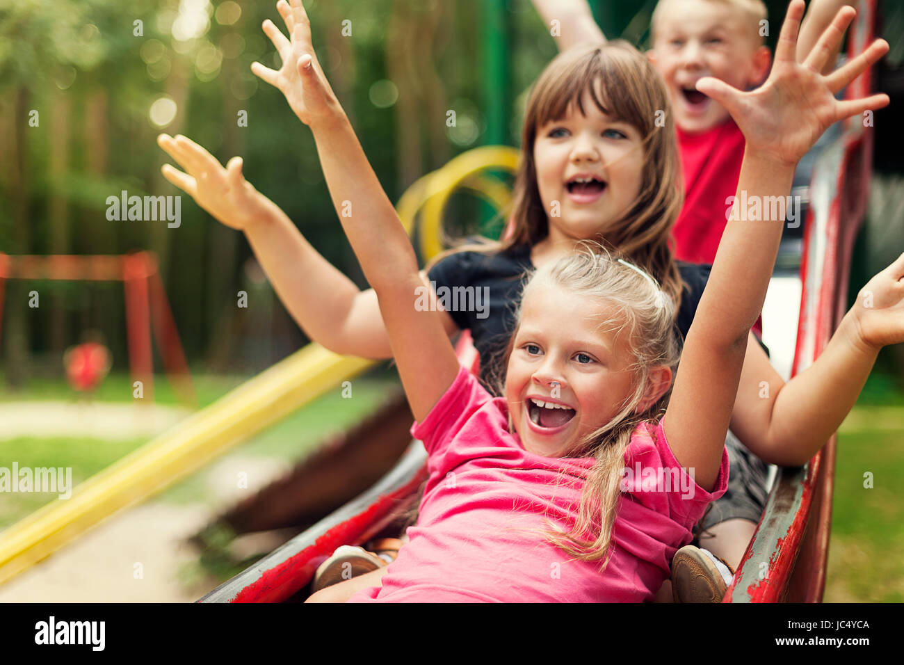 Happy kids playing on slide Stock Photo - Alamy