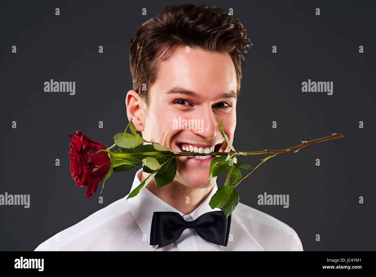 Man with a red rose in mouth Stock Photo - Alamy