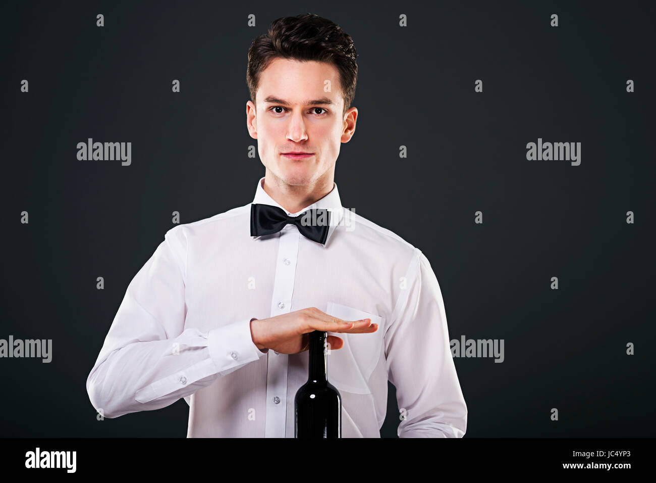 Focused waiter holding a bottle of wine Stock Photo - Alamy