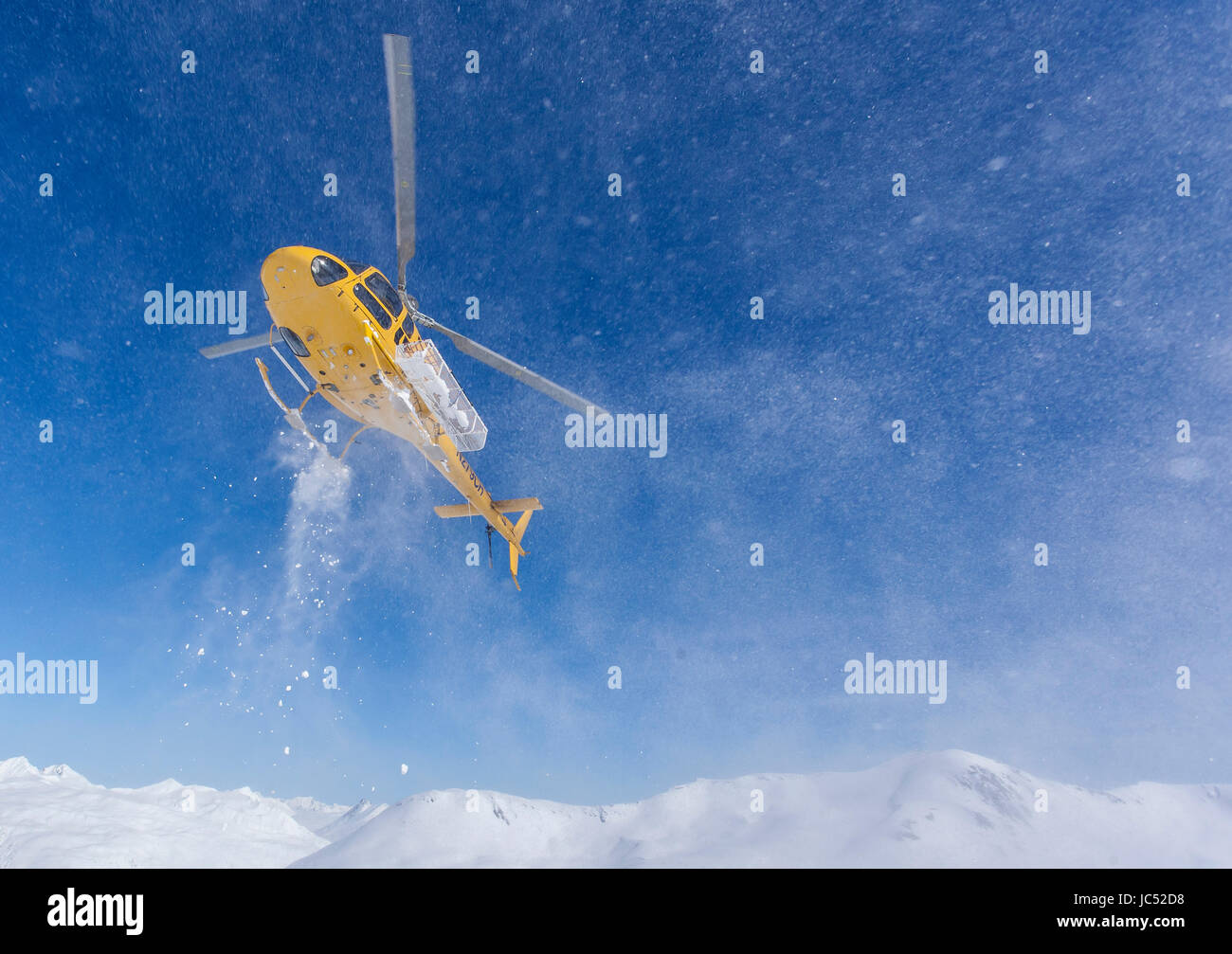 A helicopter takes and snow flies off the bottom on a sunny bluebird ...