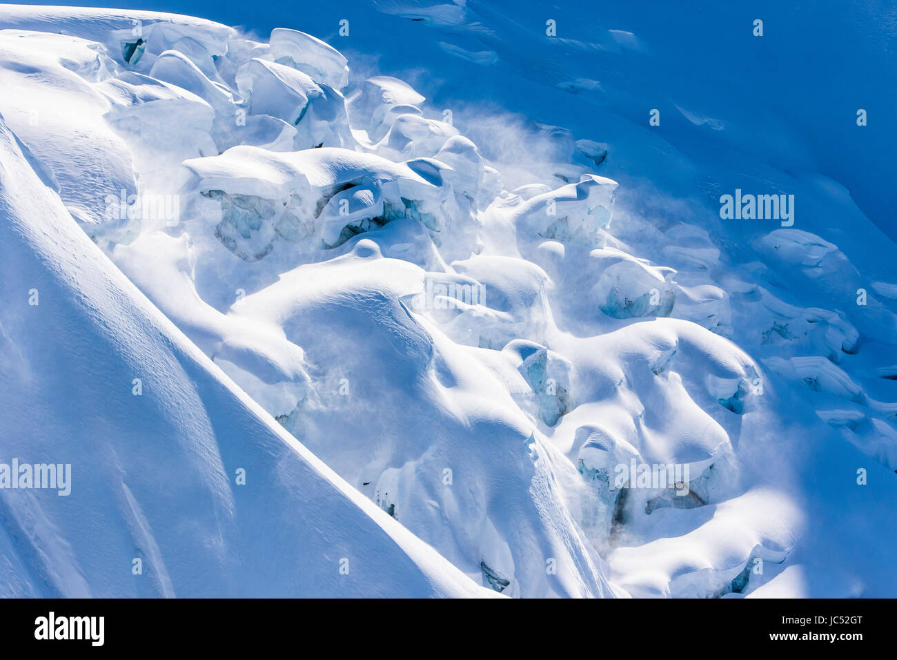 A glacier filled with crevasses is covered with a fresh layer of snow ...