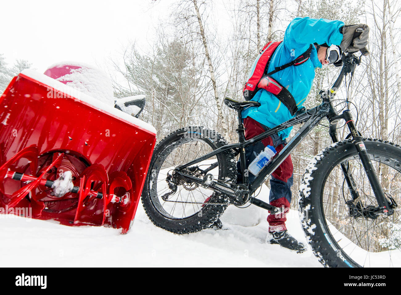 pushing a fat-tire bike by a snowblower parked in someones yard Stock ...