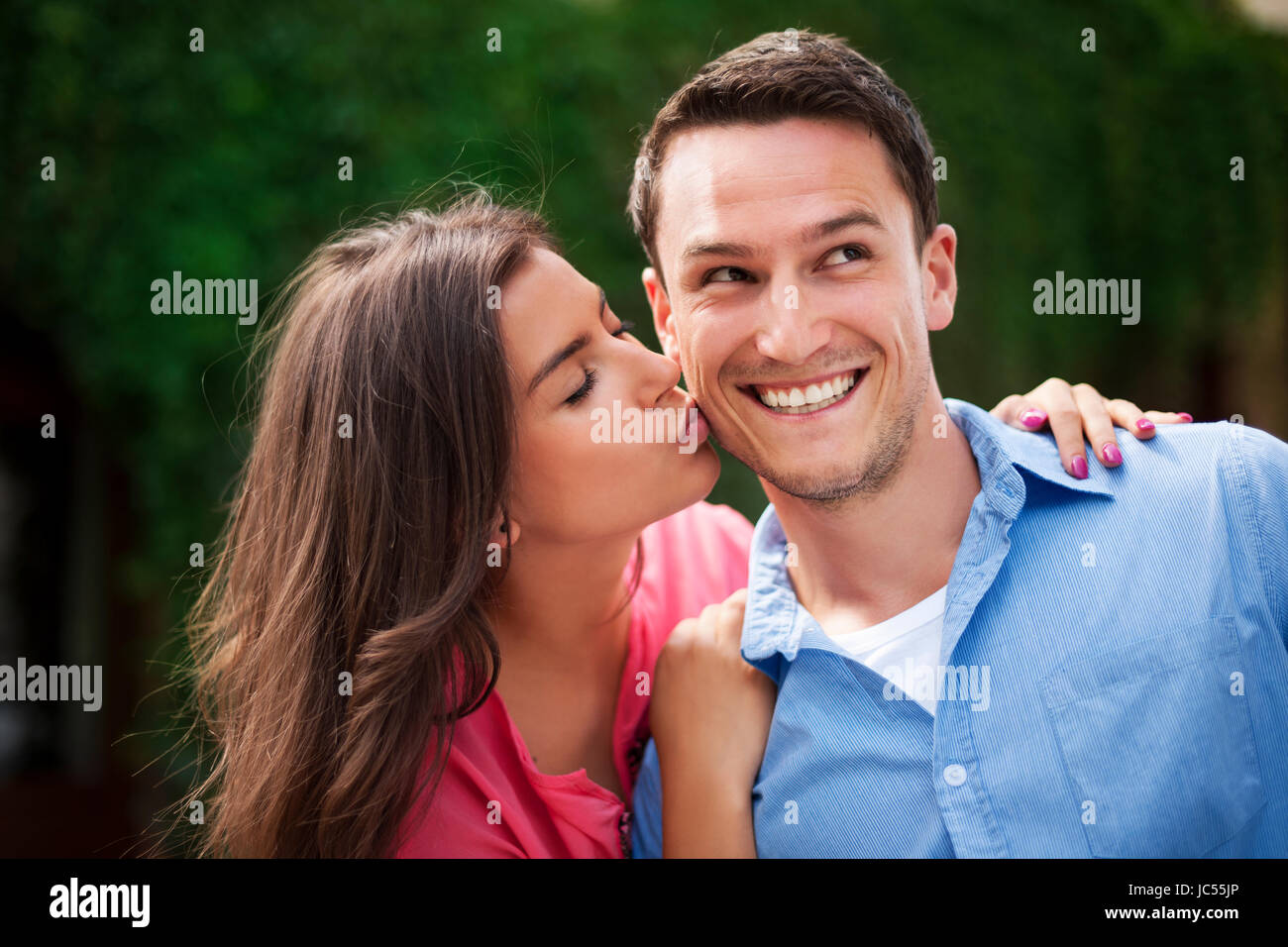 Young woman kissing her boyfriend on the cheek Stock Photo - Alamy