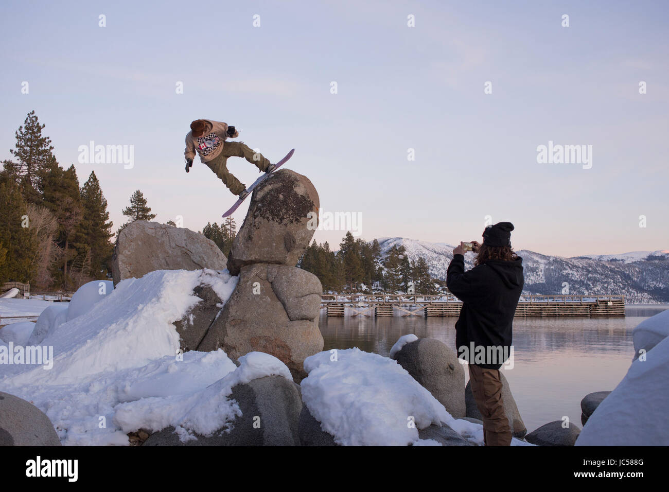 Snowboarder creates a jump at a granite boulder on Tahoe's north shore ...