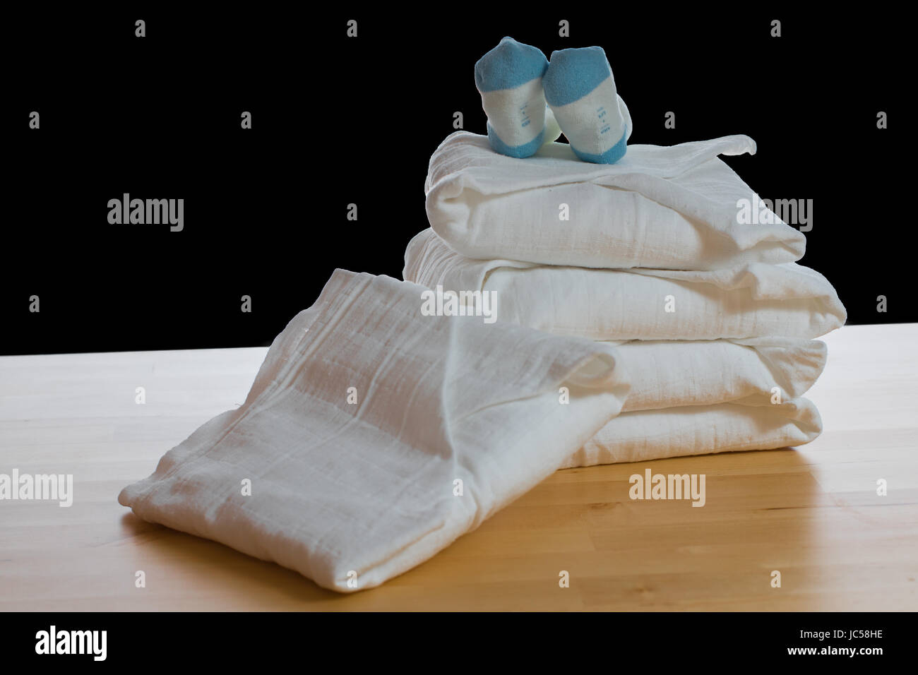 Stack of classical square white cloth diapers with blue socks on black ...