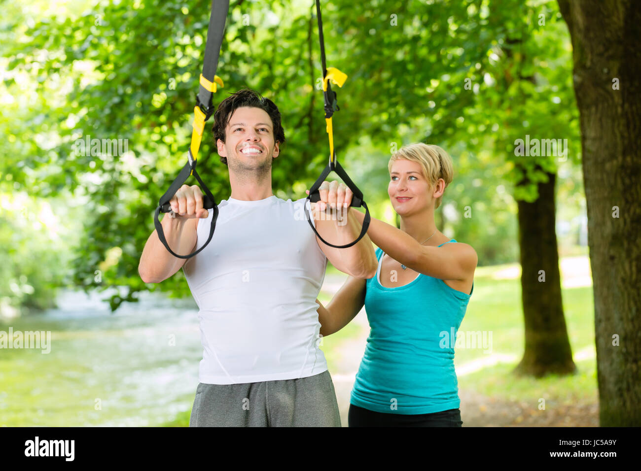 Young fitness man exercising with suspension trainer sling and personal ...