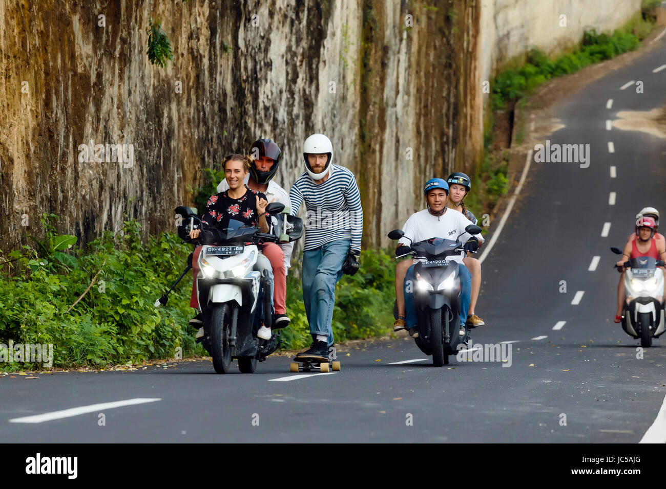 Longboarder skitching behind small group of motorbikes Stock Photo - Alamy